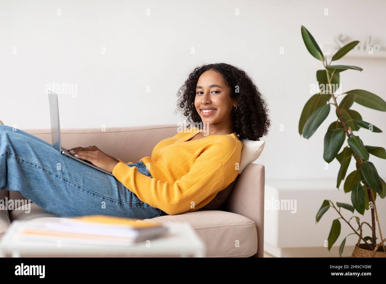 Cheerful young black female communicating online via laptop computer ...