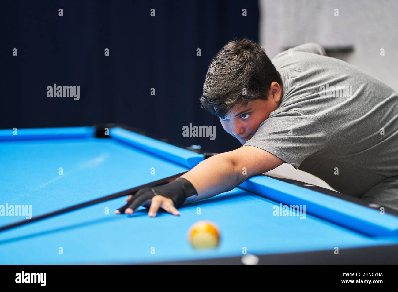 Serious boy in casual wear with cue stick preparing to hit ball while ...