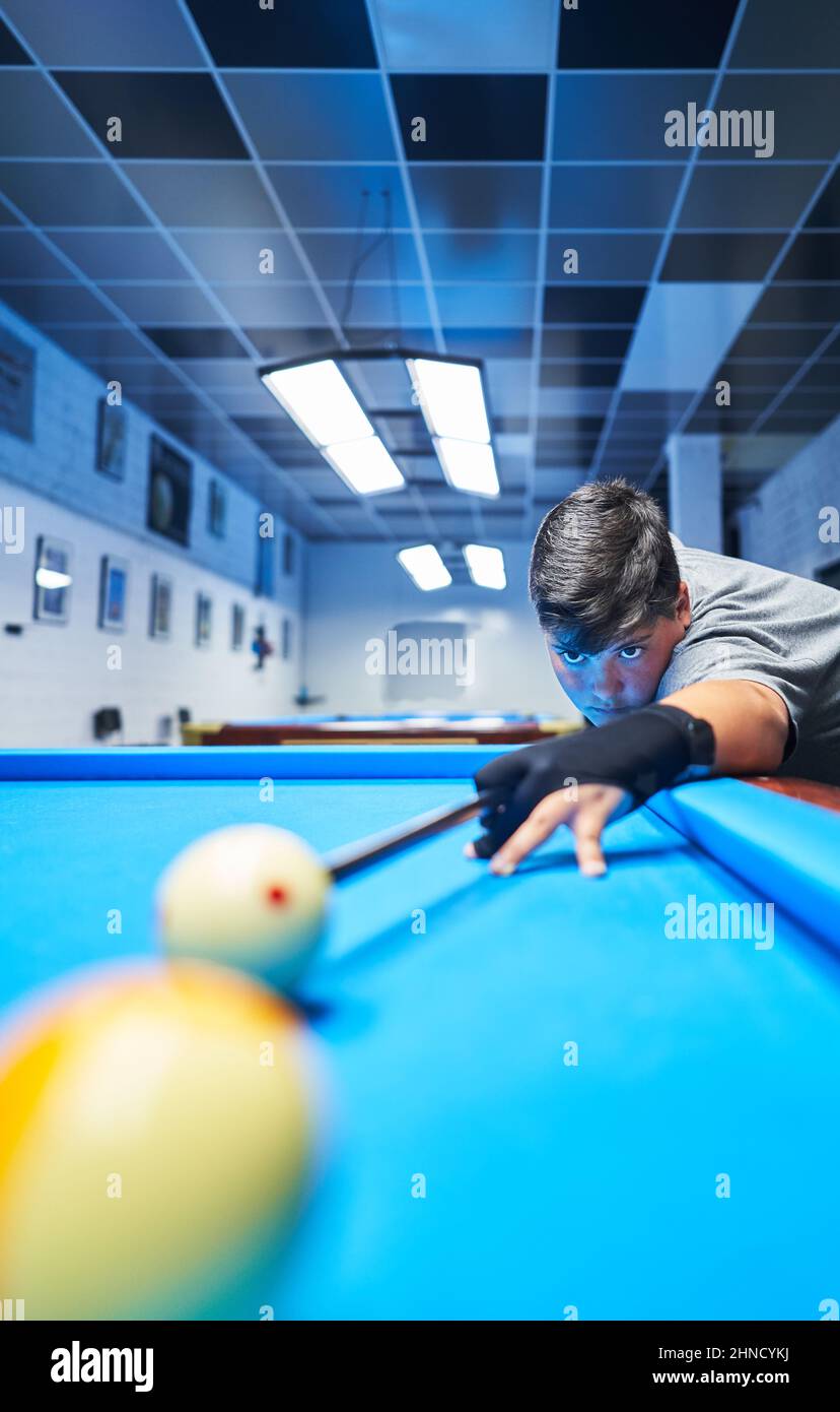 Serious boy in casual wear with cue stick preparing to hit ball while ...