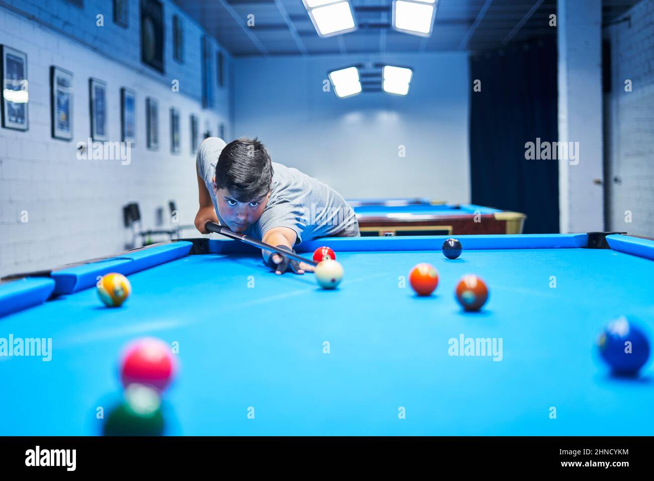 Serious boy in casual wear with cue stick preparing to hit ball while ...