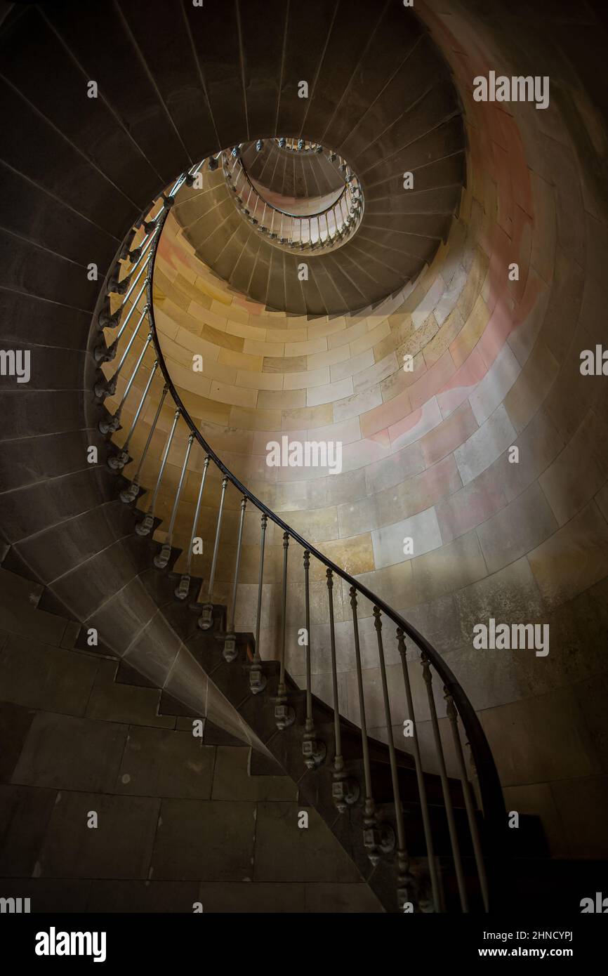 Long spiral stairway with stone steps and metal railing placed in high ...