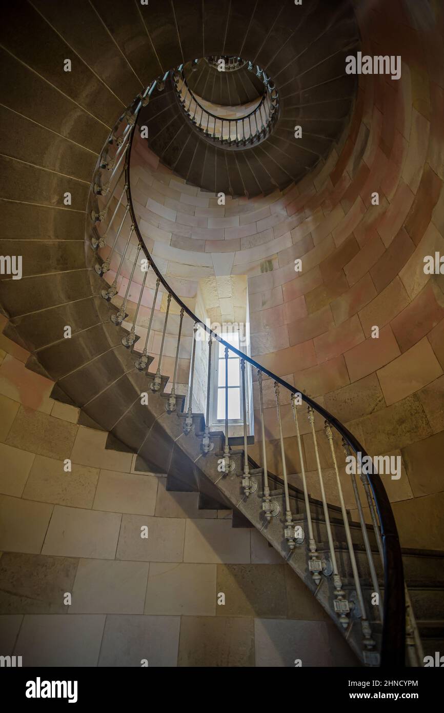 Long spiral stairway with stone steps and metal railing placed in high ...