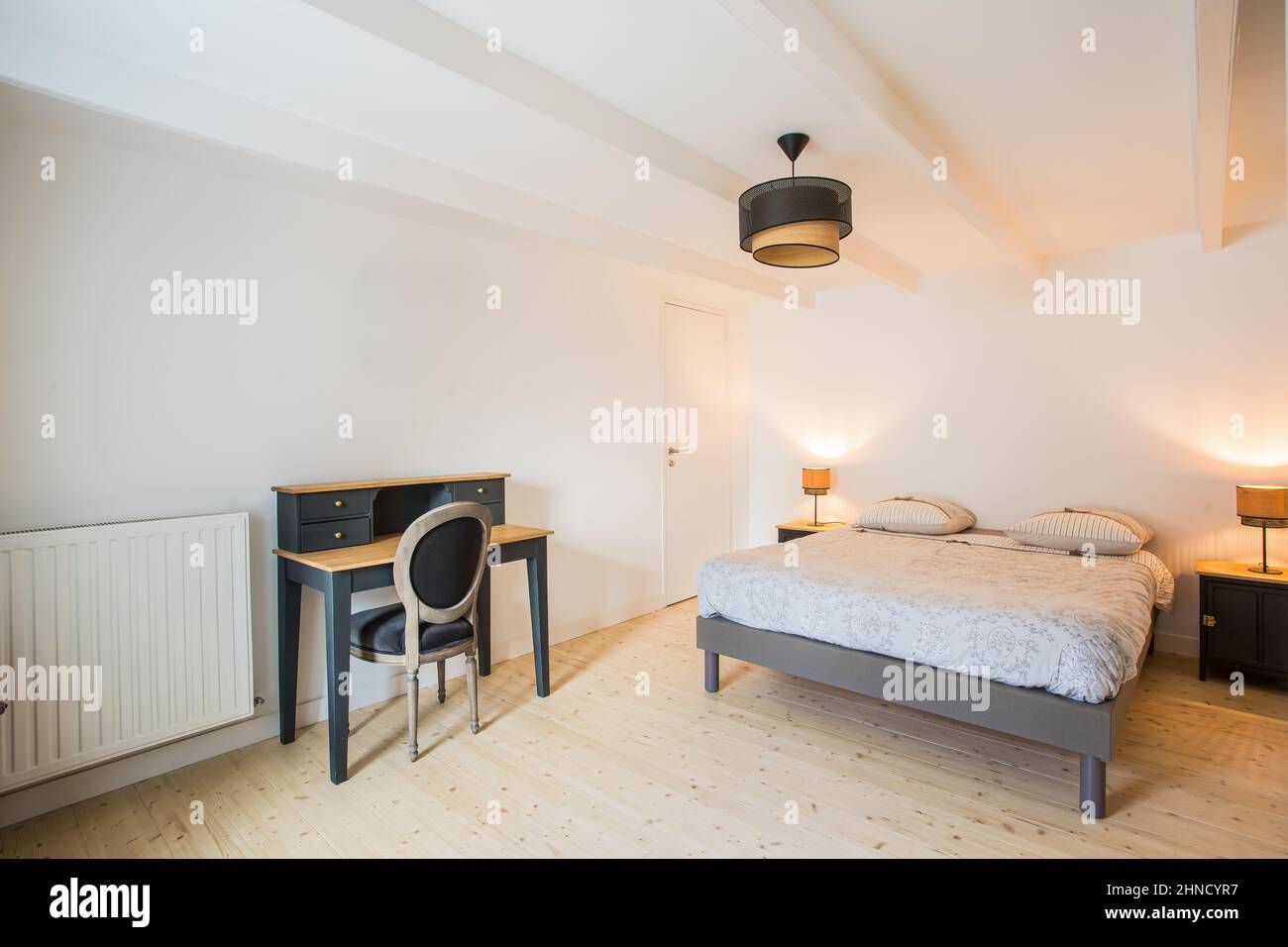 Comfortable bed with cushions placed near black secretary desk with ...