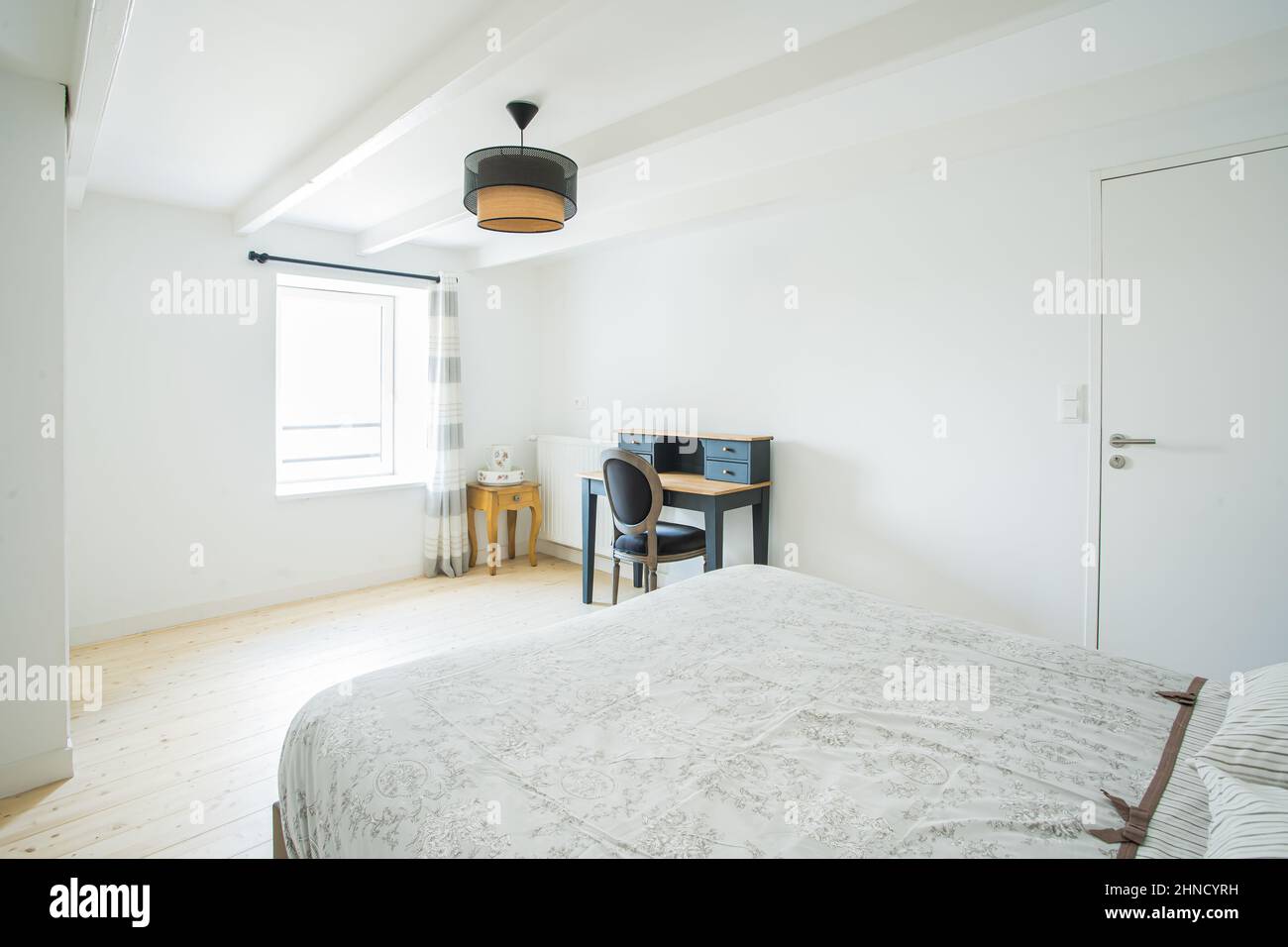 Comfortable bed with cushions placed near black secretary desk with ...