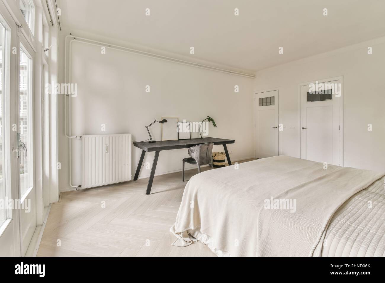 Comfortable bed and lamps on bedside tables and chair with desk near ...