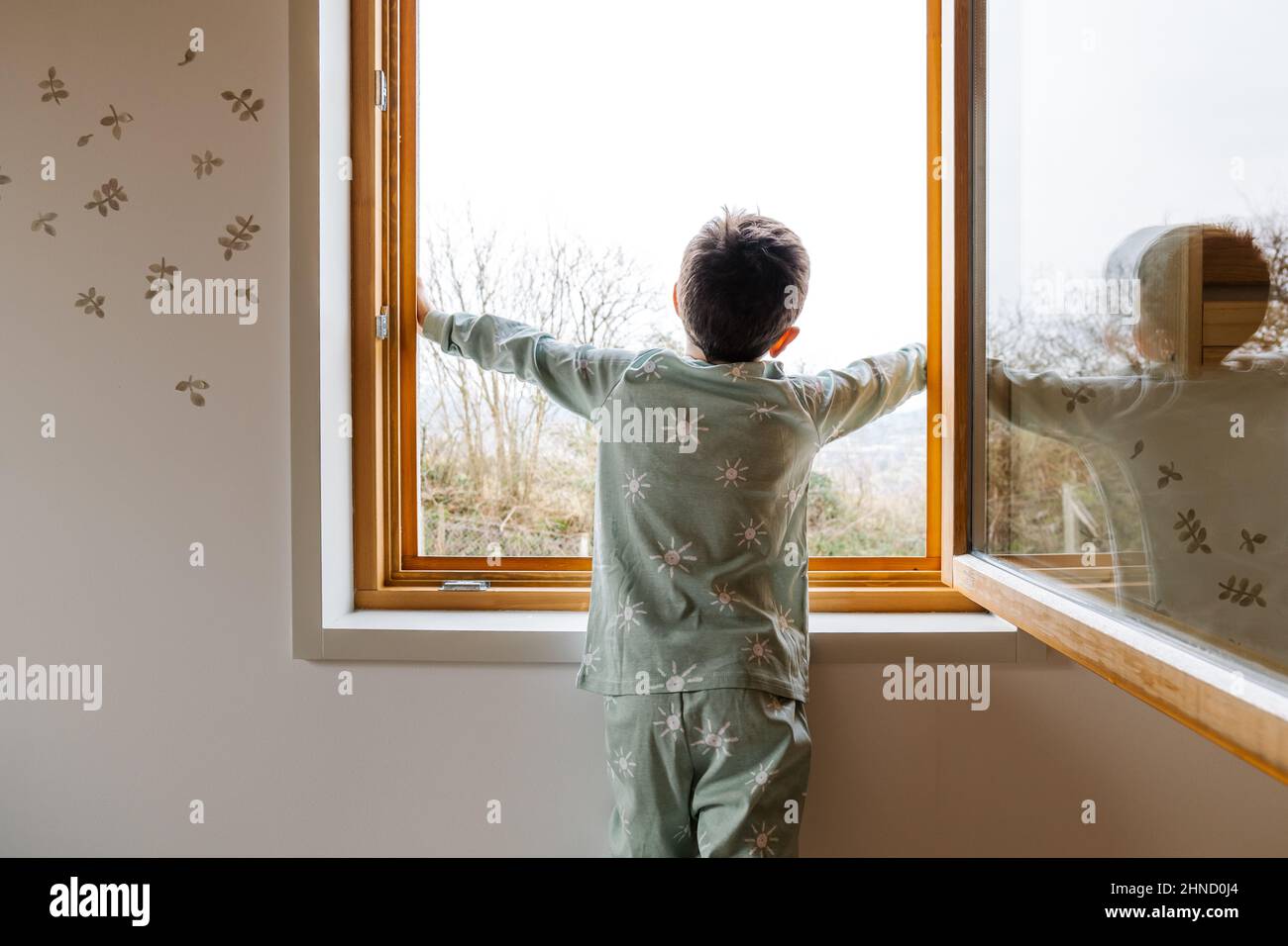 Back view of cropped unrecognizable cute boy in nightwear looking out ...