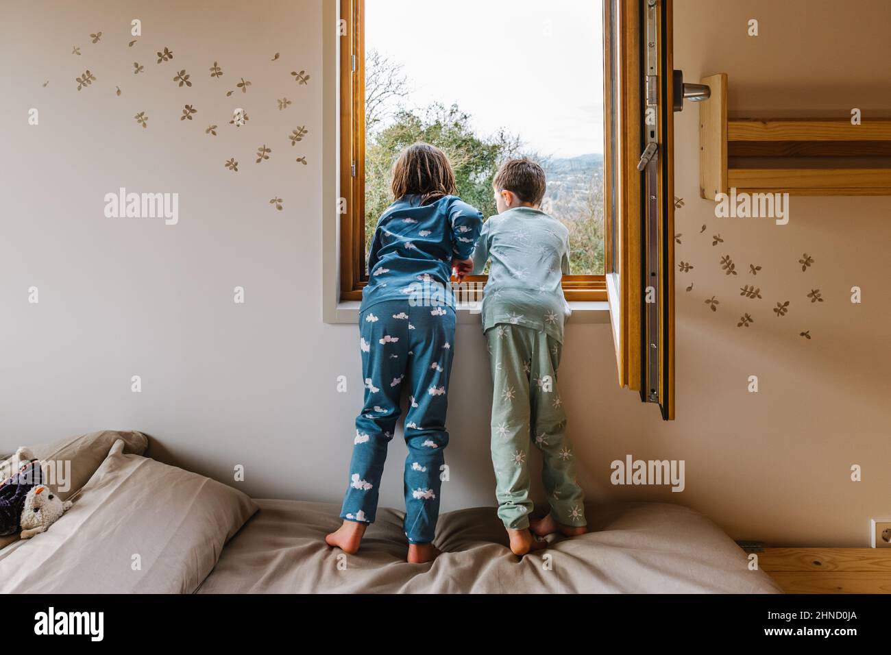 Full body back view of anonymous curios children in nightwear looking ...