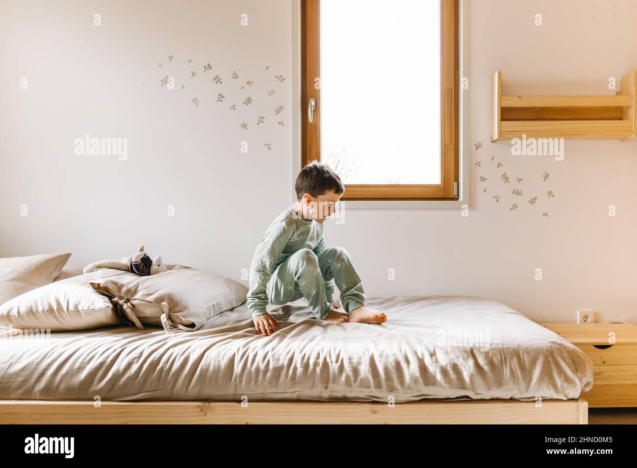 Full Body Of Positive Barefoot Boy In Pajama Looking Away While Sitting 7502