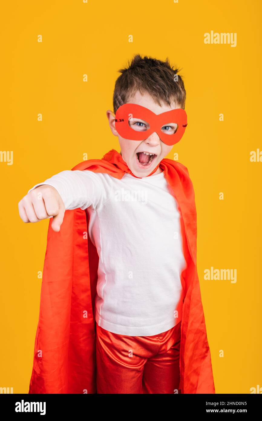 Child in red superhero clothes and mask stretching arm while standing ...
