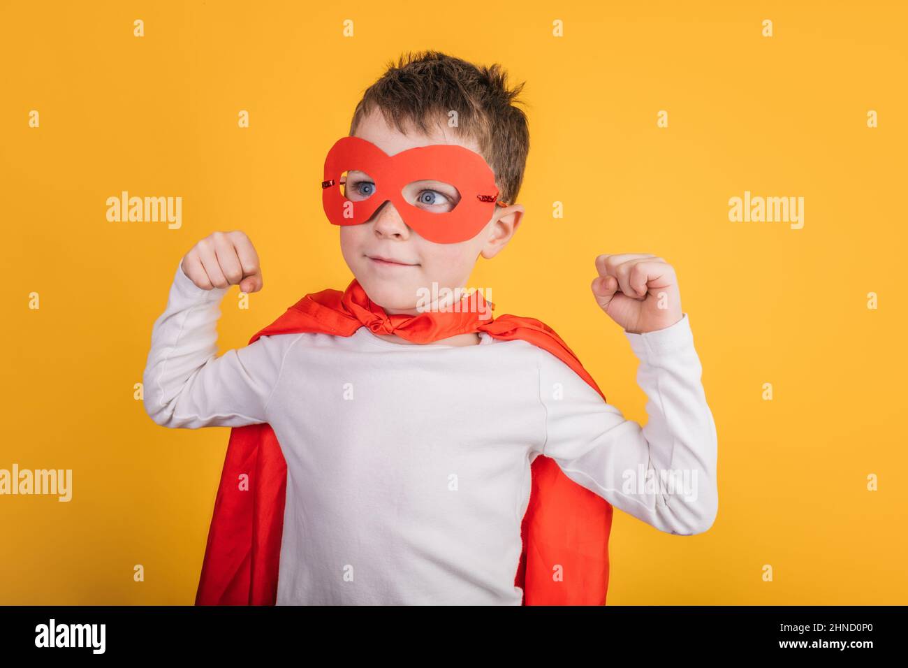 Little kid in superhero suit demonstrating power and looking away on ...