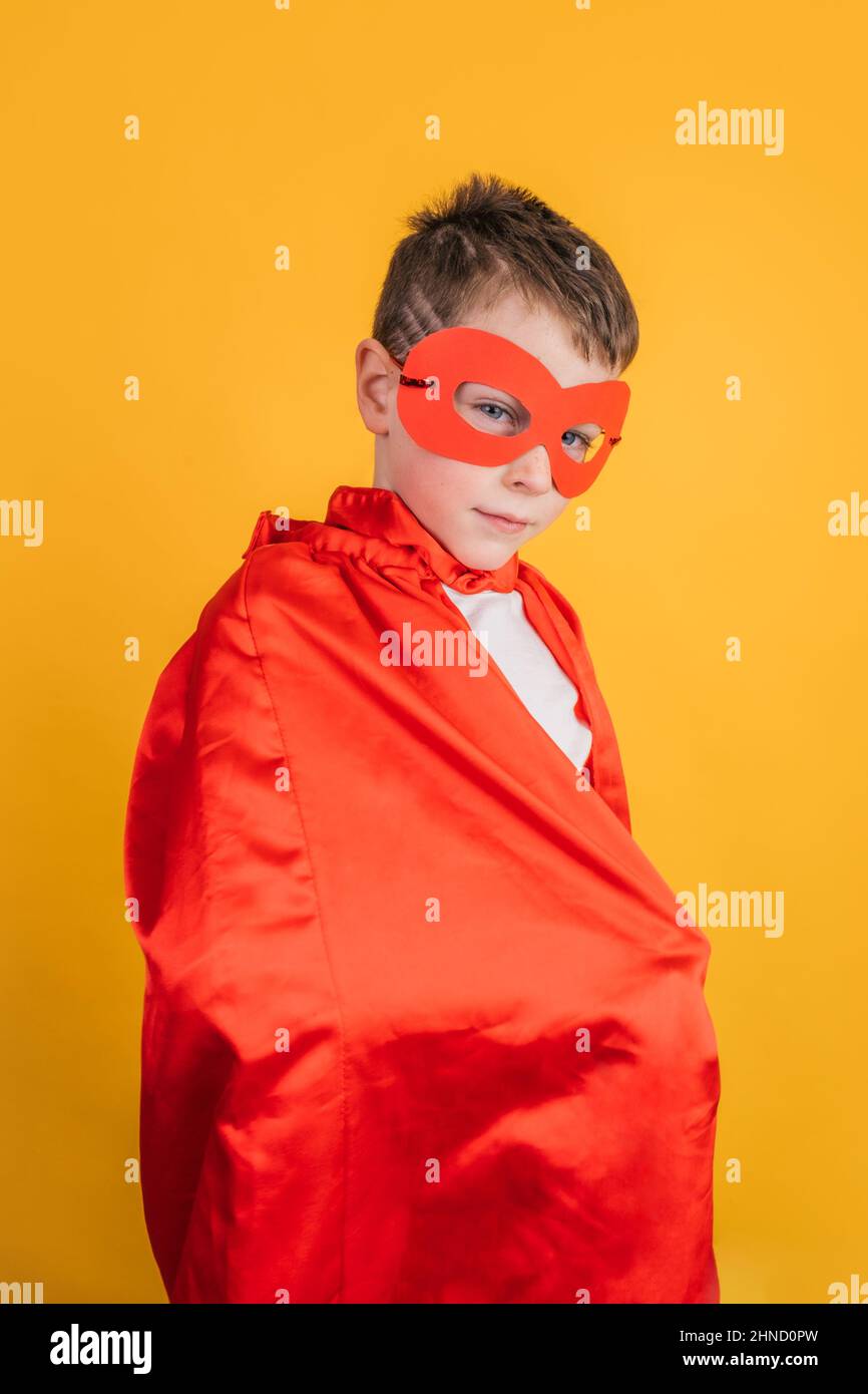 Little child wearing superhero mask and red cloak while looking at ...