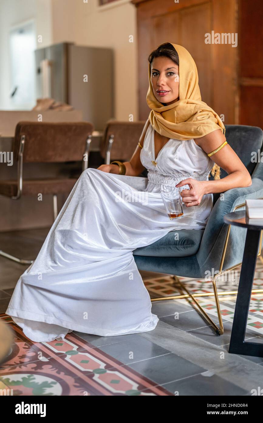 Full body of Muslim female in traditional hijab looking at camera while ...