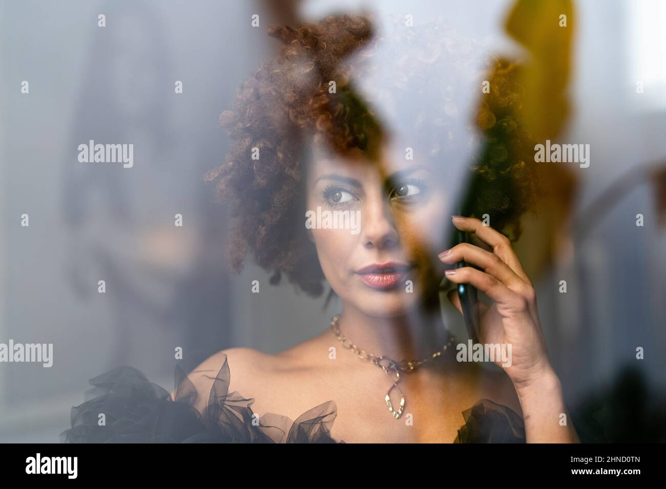 Elegant female with curly short hair answering phone call and looking ...