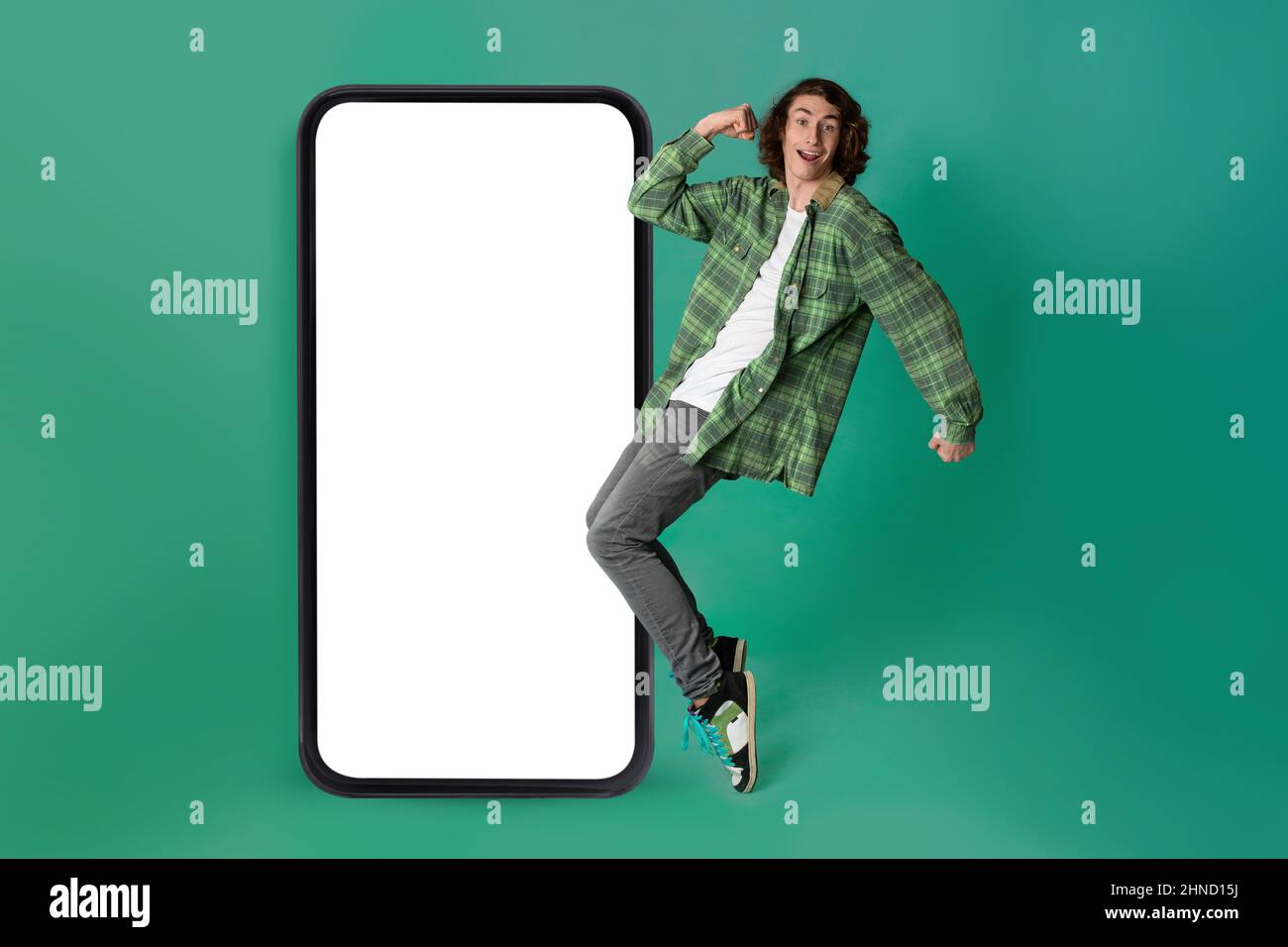 Happy guy dancing near big smartphone with blank white screen ...