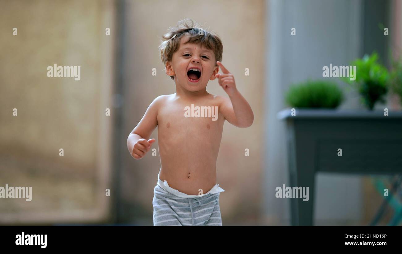 Adorable little boy running outside in slow-motion towards camera happy ...