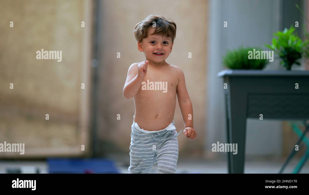 Adorable little boy running outside in slow-motion towards camera happy ...