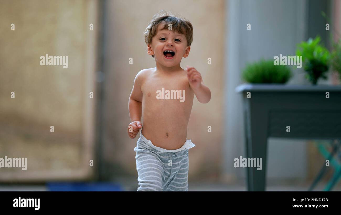 Adorable little boy running outside in slow-motion towards camera happy ...