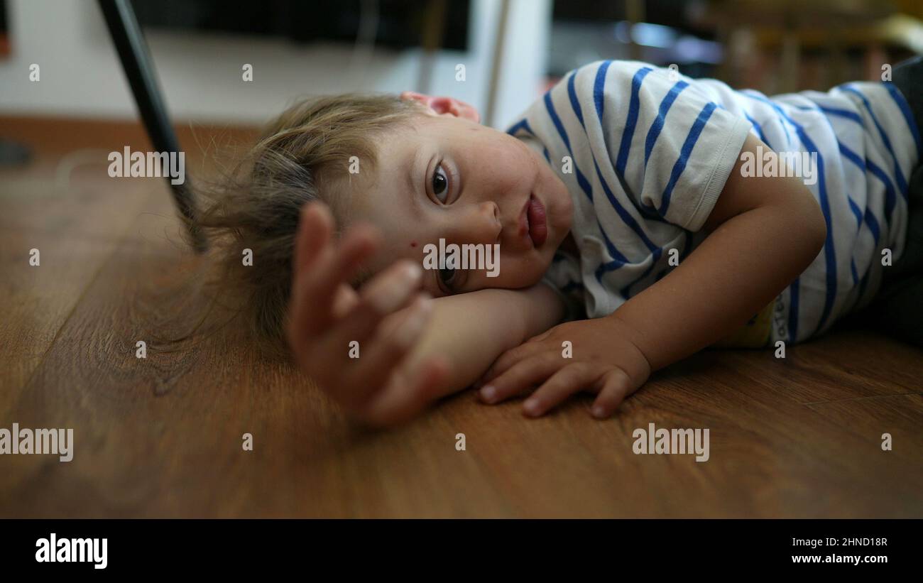 Bored little boy lying on floor at home child having nothing to do ...