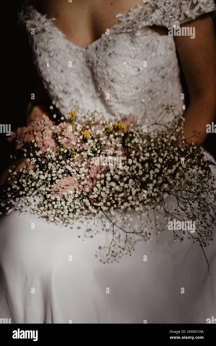 From above anonymous bride in elegant white dress with fresh bouquet ...