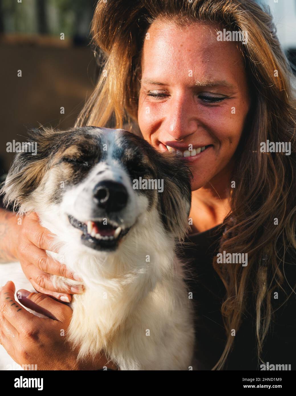 Positive female owner hugging cute hairy Australian Shepherd dog with ...