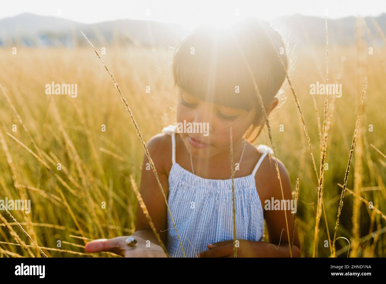 Adorable Hispanic kid playing small stone in hand while resting in ...