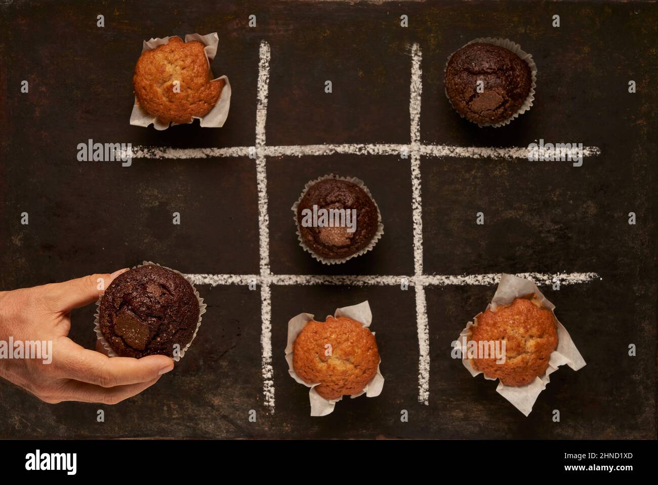 Top view of crop anonymous person putting chocolate muffin in grid ...