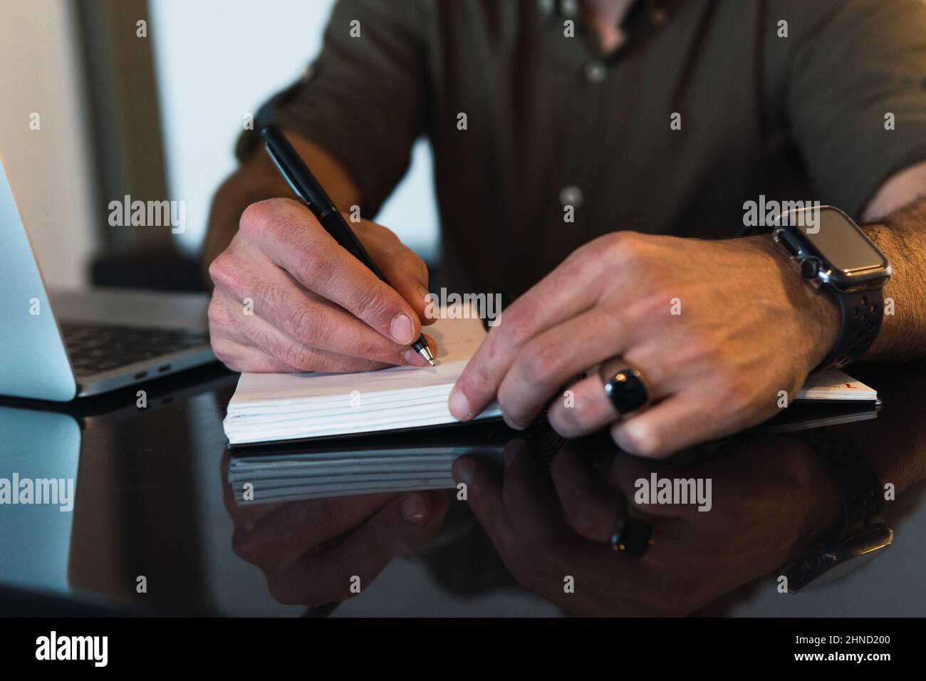 Crop unrecognizable male taking notes in notepad while sitting at table ...