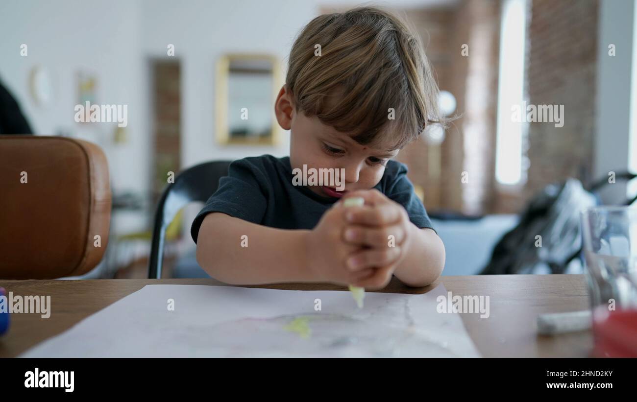 Child playing with art craft at home pressing paint into paper Stock ...