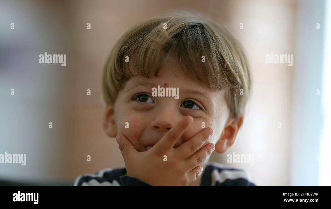 Child reaction with unbelief covering mouth with hand in disbelief ...