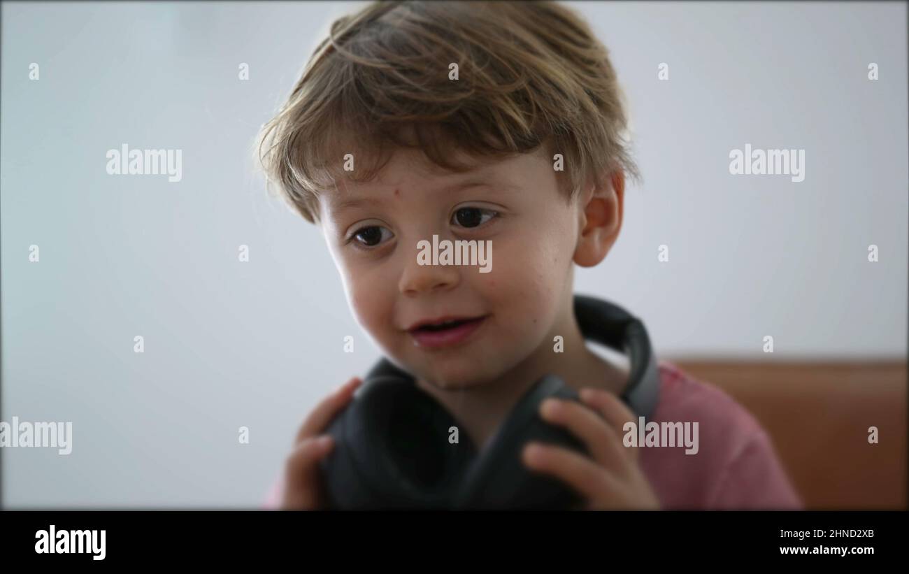 Child removing headphones from ear kid taking takes off headphones ...