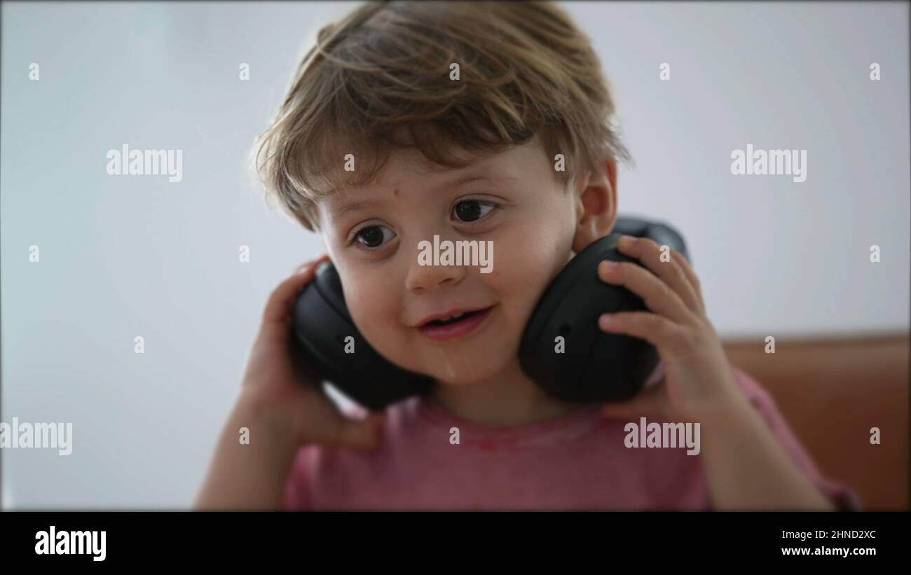 Child removing headphones from ear kid taking takes off headphones ...
