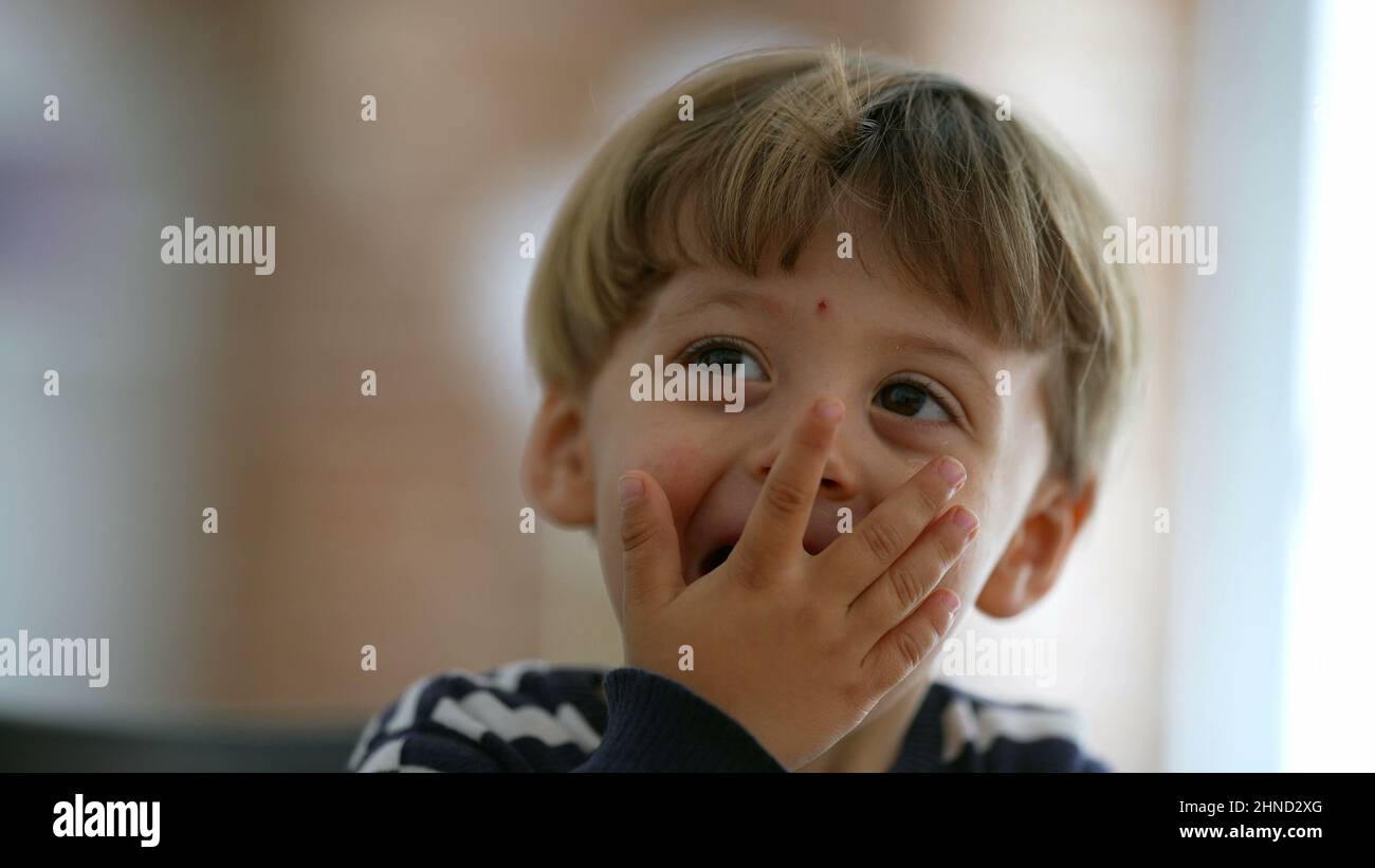Child reaction with unbelief covering mouth with hand in disbelief ...