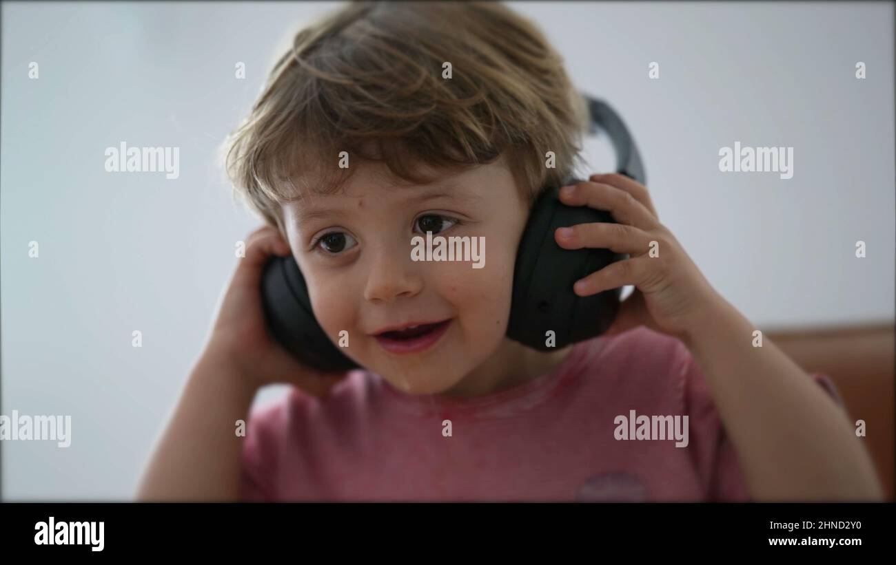 Child removing headphones from ear kid taking takes off headphones ...