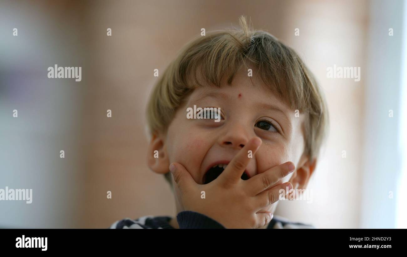 Child reaction with unbelief covering mouth with hand in disbelief ...