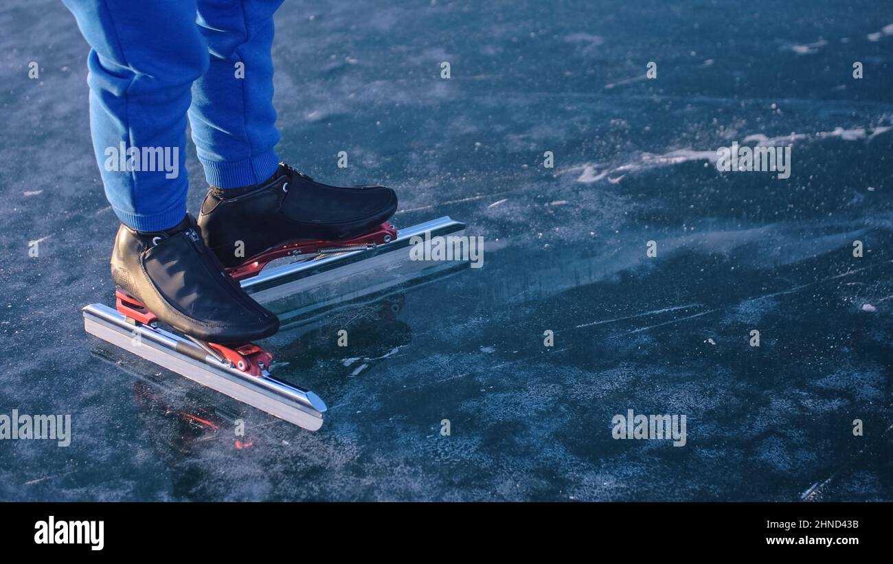 The child train on ice speed skating. The legs in skates close up. The ...
