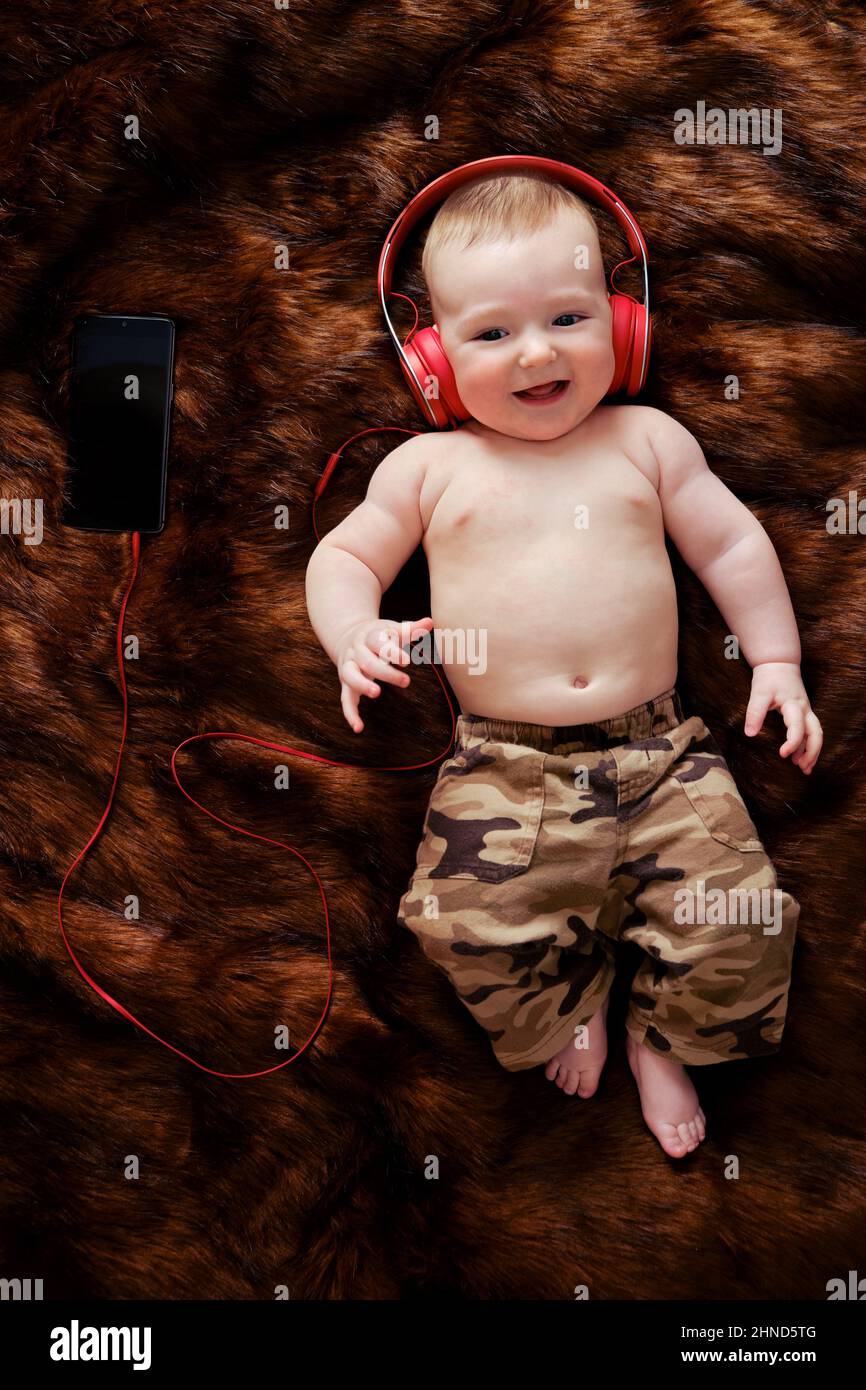 Funny happy baby boy listens to music in wired headphones online from ...