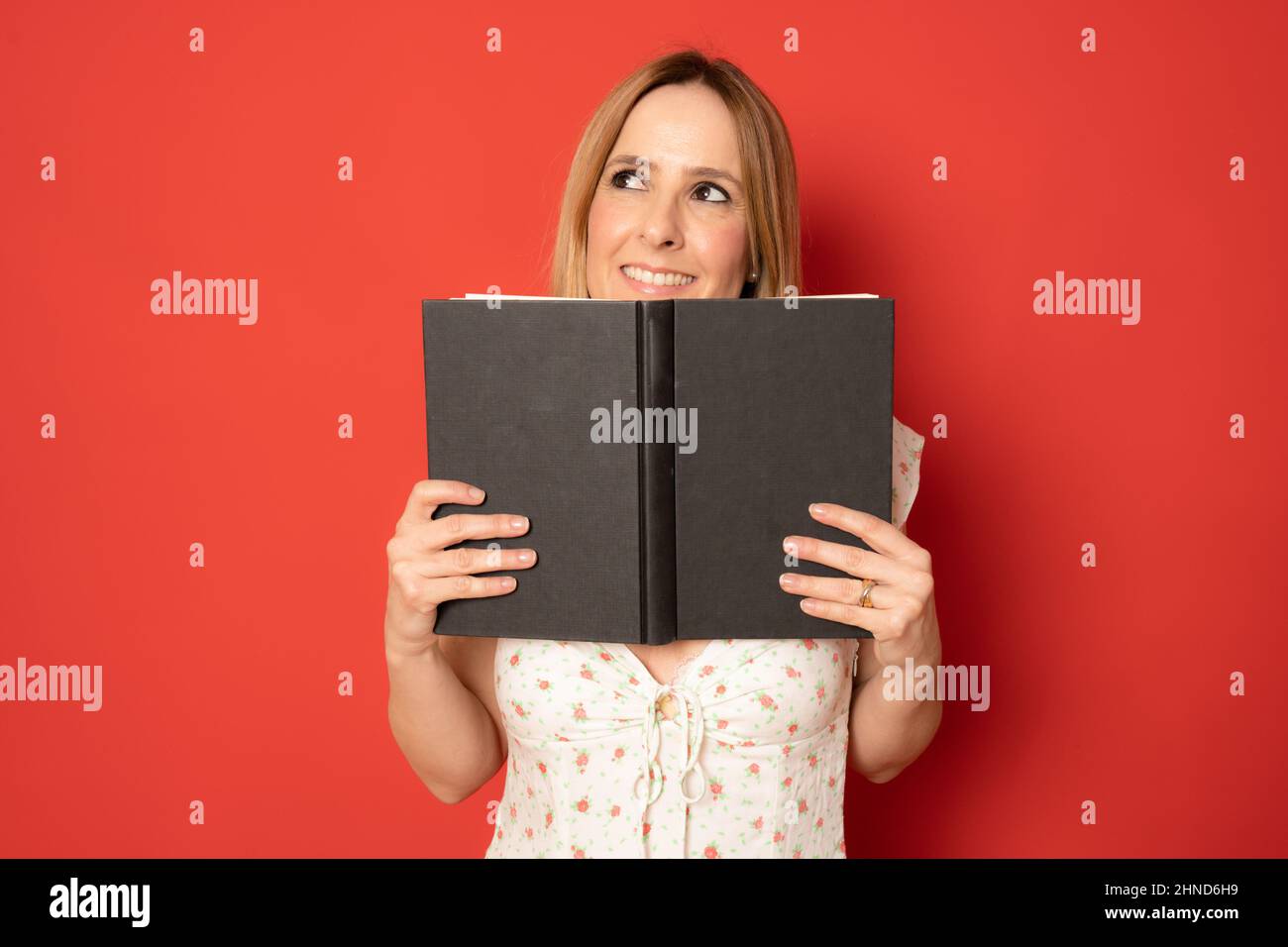 Beautiful young woman in casual dress reading a book standing isolated ...