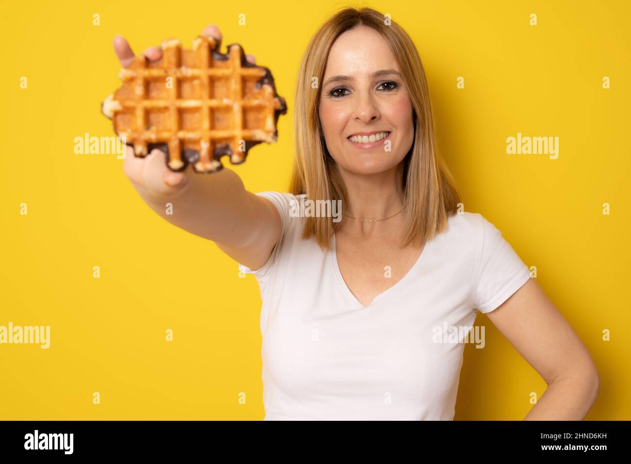 Close up portrait of a young beautiful woman showing sweet waffle ...