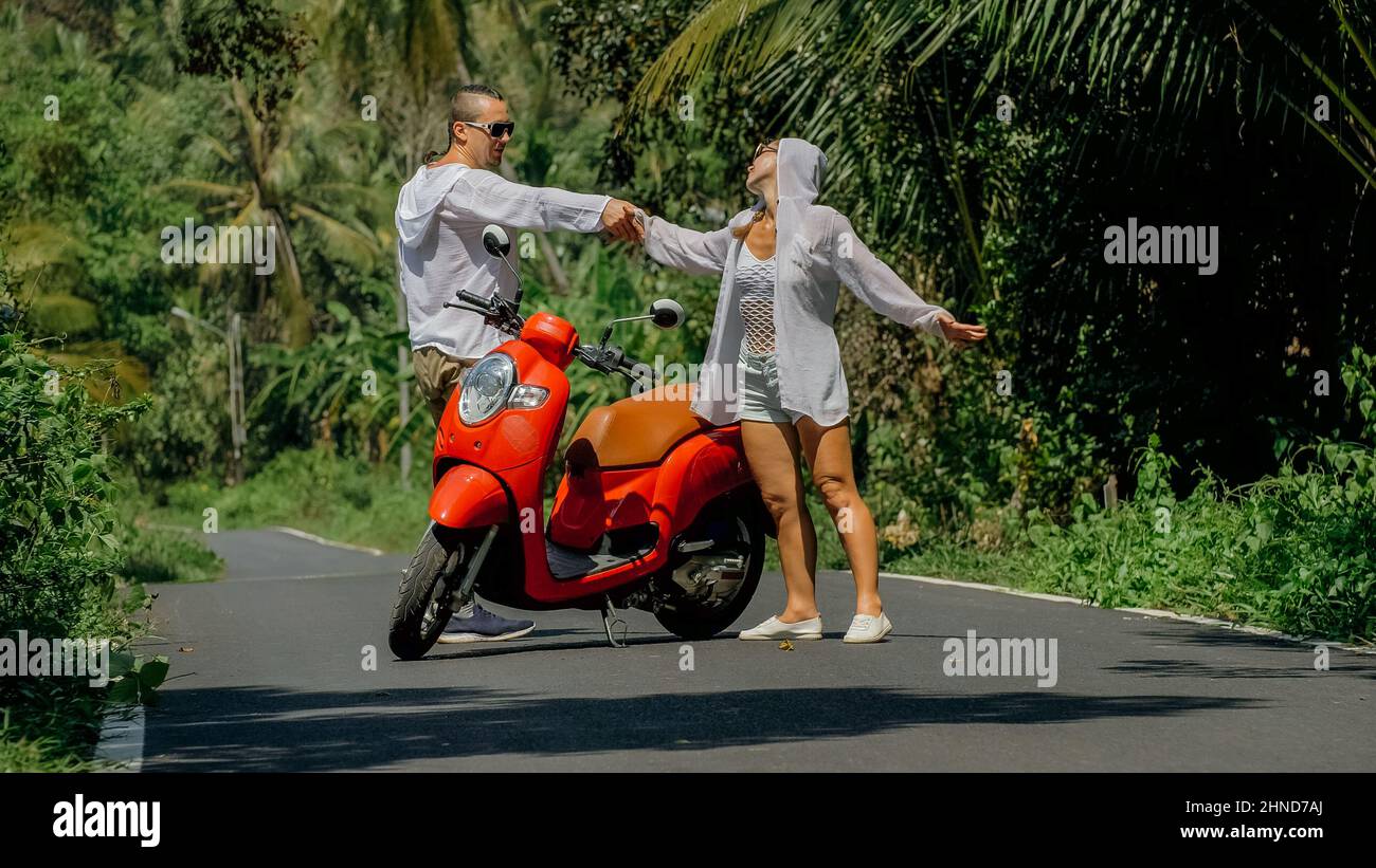 Two caucasian tourist woman man dance near scooter. Love couple on red ...