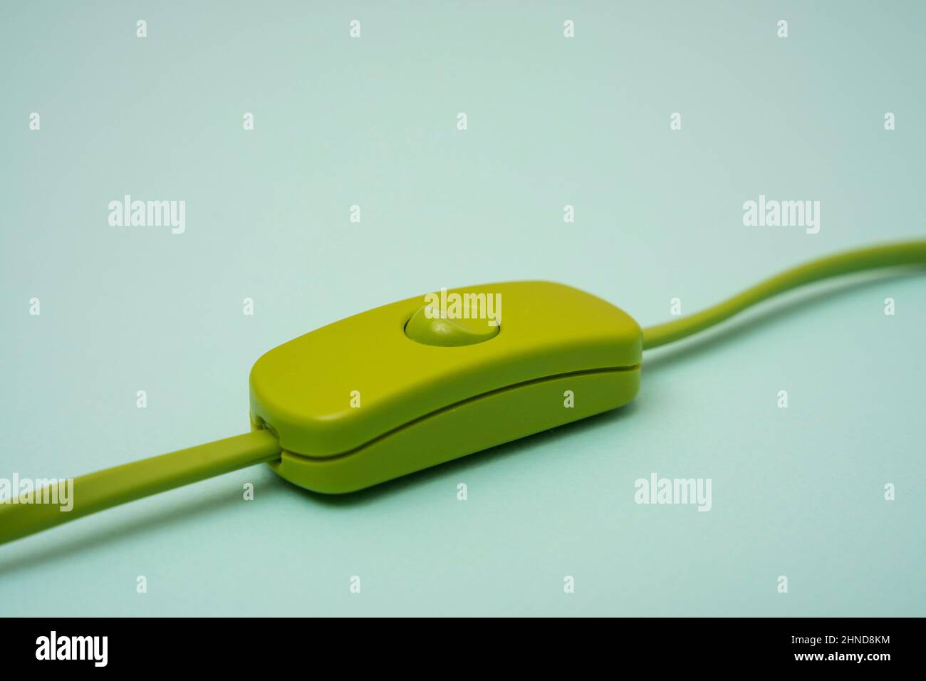 green electric wire with switch on turquoise background, copy space ...