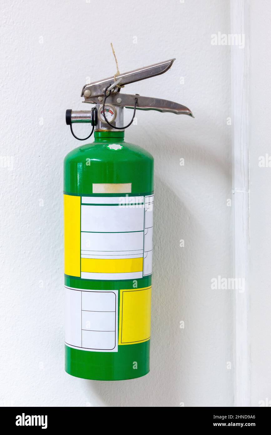 Closeup of the green fire extinguisher on the white wall of the office ...