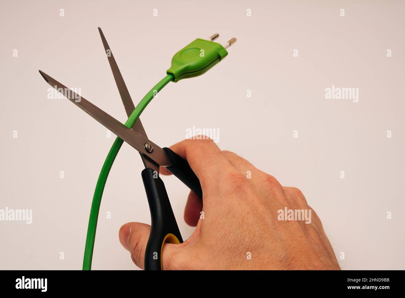 a hand with office scissors cuts an electric wire, danger, violation ...