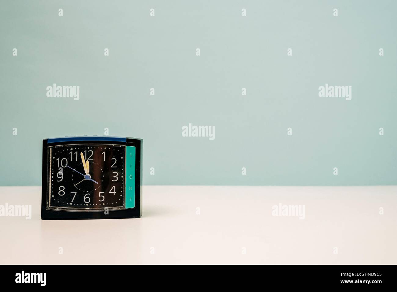 square modern alarm clock on the table on a turquoise background, time ...
