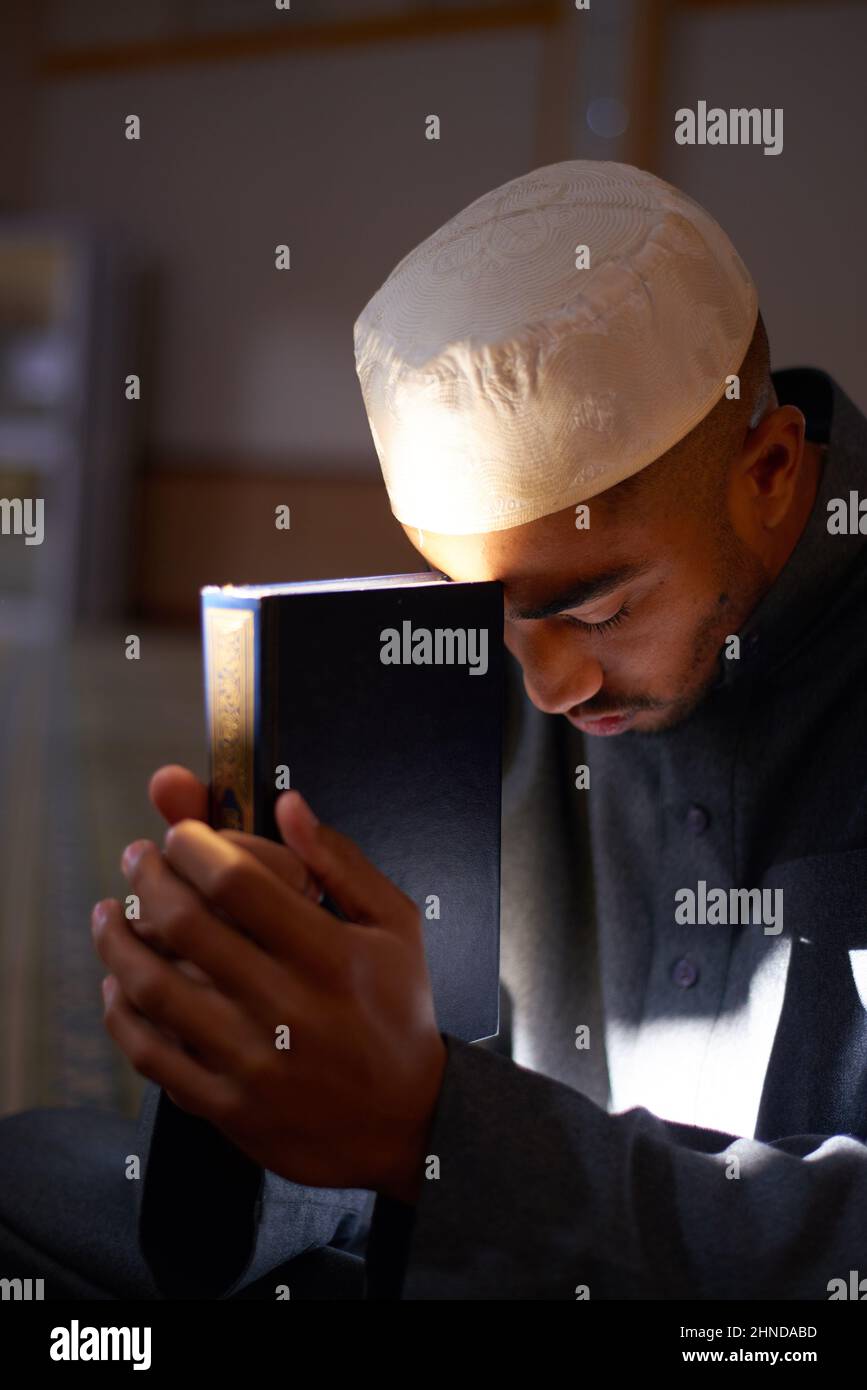 A young Muslim male holds the Quran to his forehead Stock Photo - Alamy