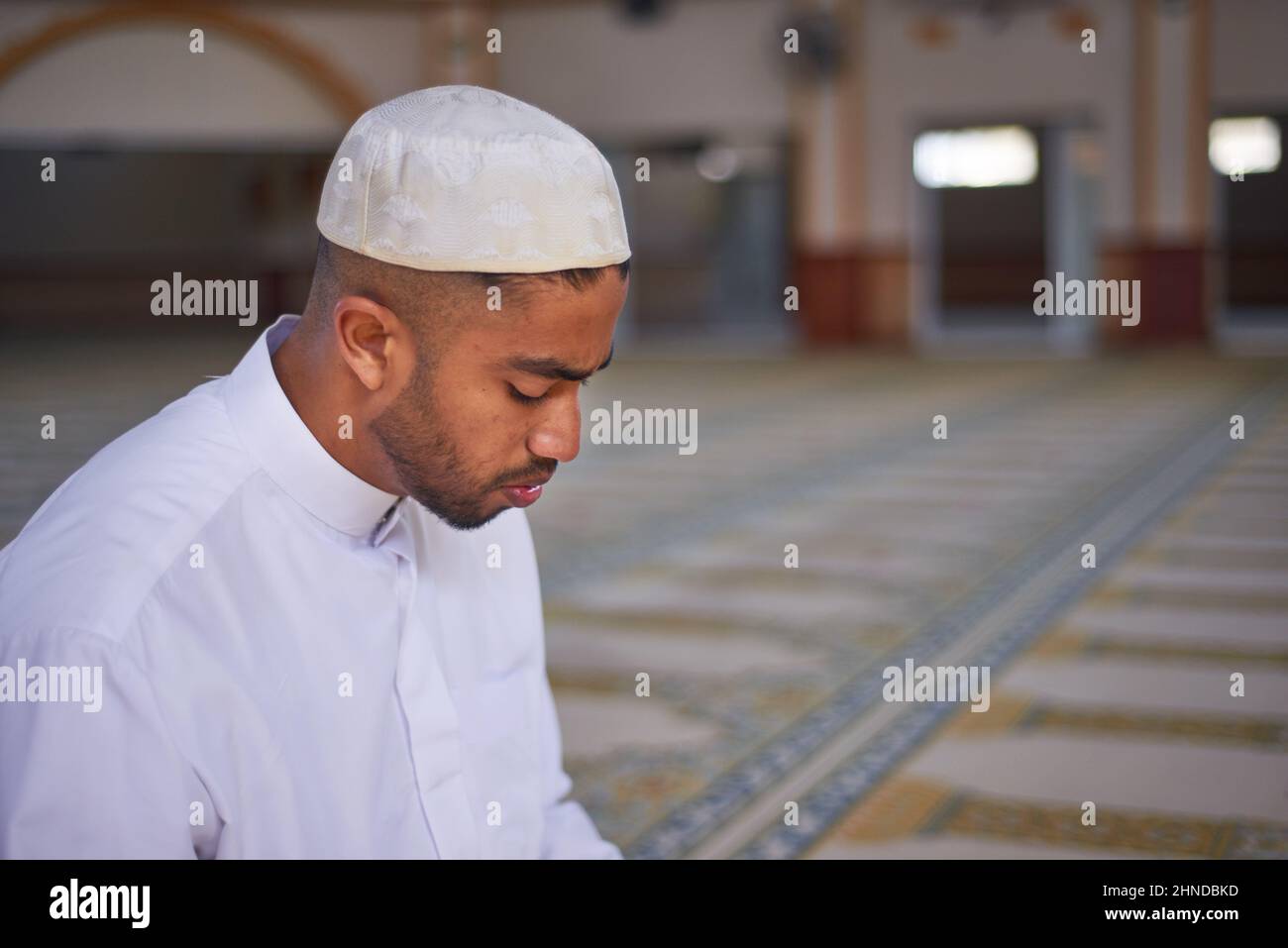 A Muslim man bows his head in prayer while kneeling in a mosque in the ...
