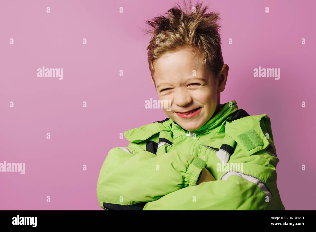 laughing disheveled European boy of five years in a winter green jacket ...