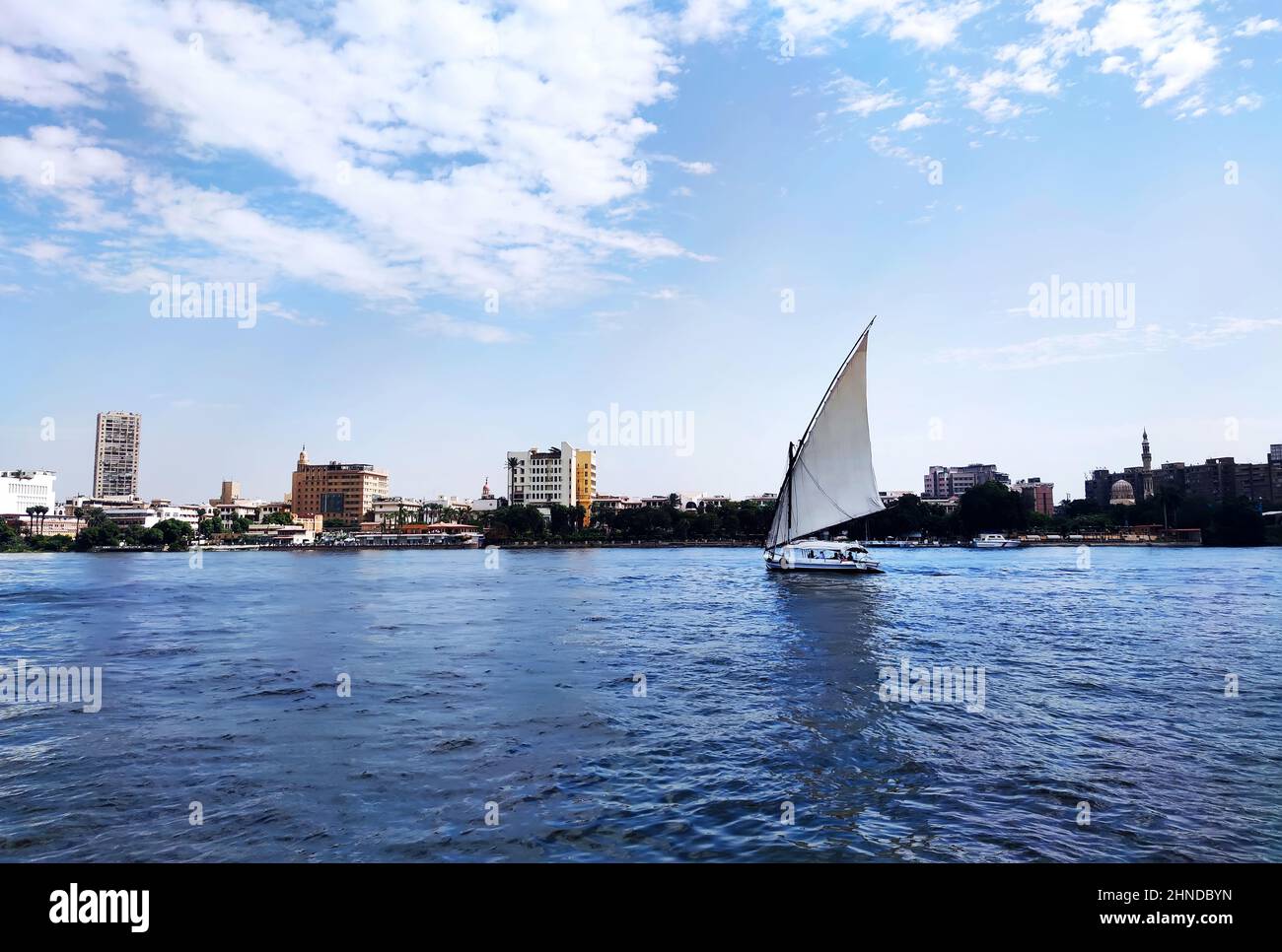 A sailboat on a river walk sails along the Nile River in the center of ...