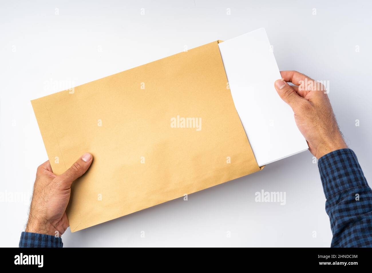 Top view of male hands hold (open) an envelope above white background ...