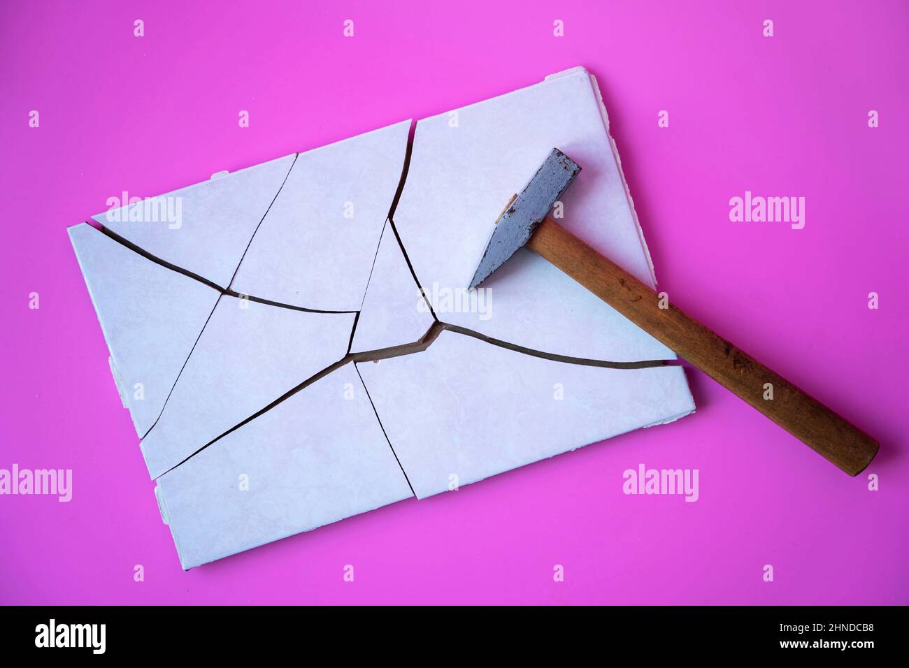 Tile broken into pieces with a hammer on a pink background, tile ...