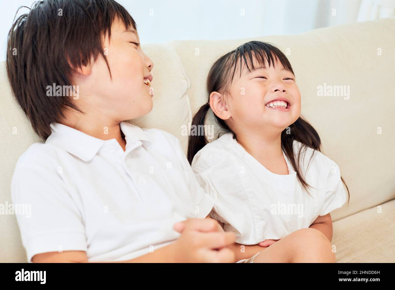 Japanese Brother And Sister Relaxing On The Sofa Stock Photo - Alamy